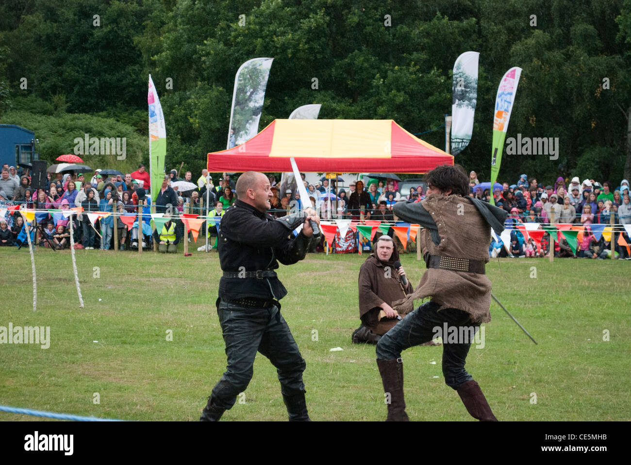 Two men in medieval costume sword fighting at jousting tournament with ...