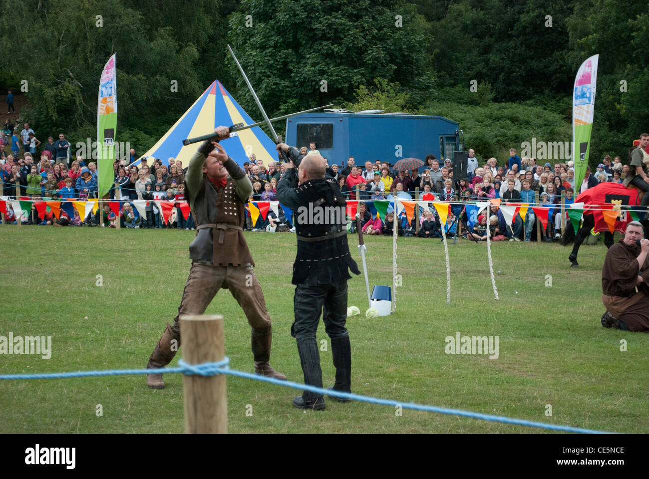 Two men in medieval costume sword fighting at jousting tournament with ...