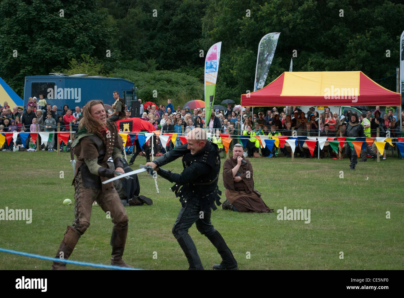 Two men in medieval costume sword fighting at jousting tournament with ...