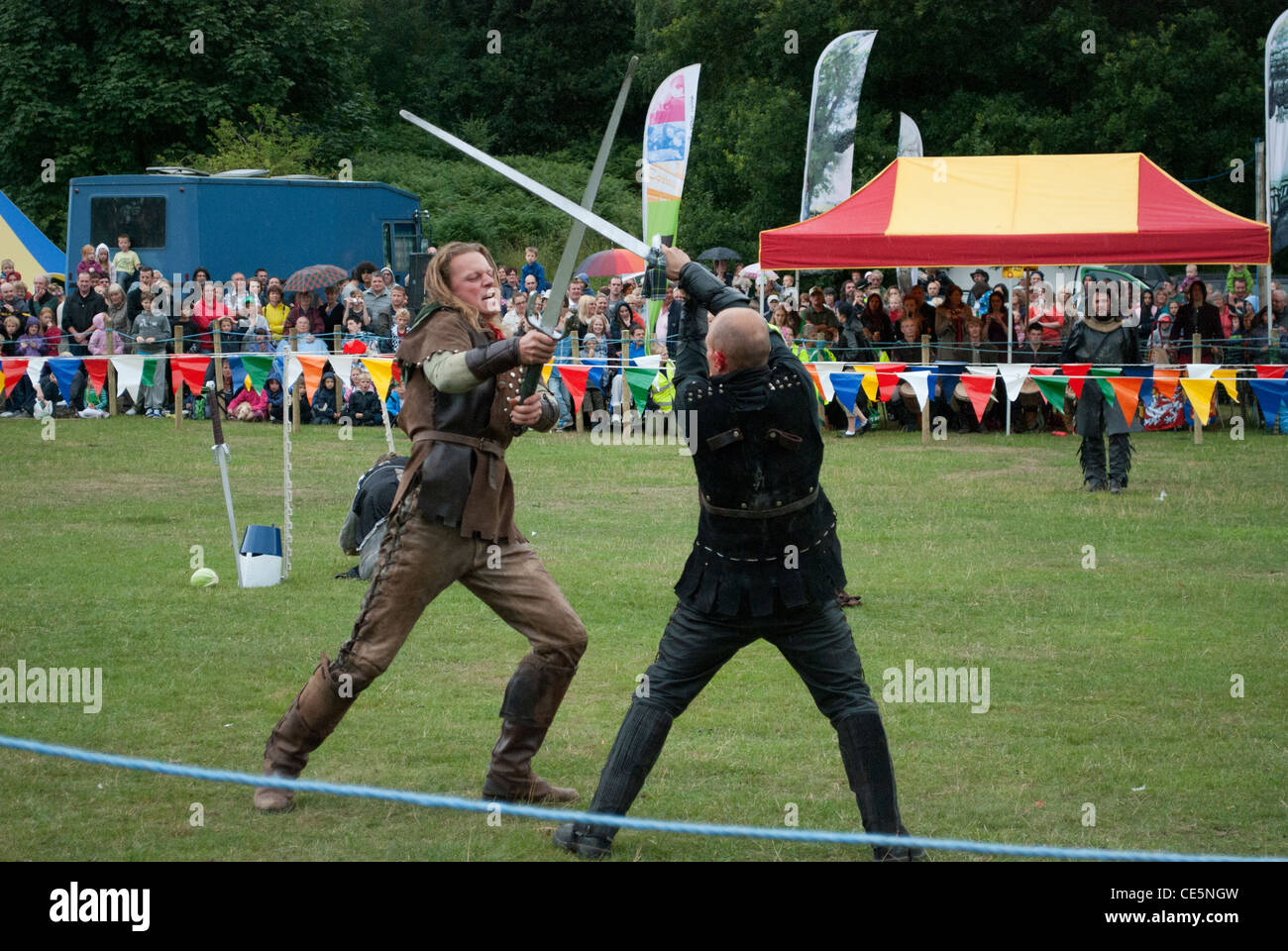 Two men in medieval costume sword fighting at jousting tournament with ...