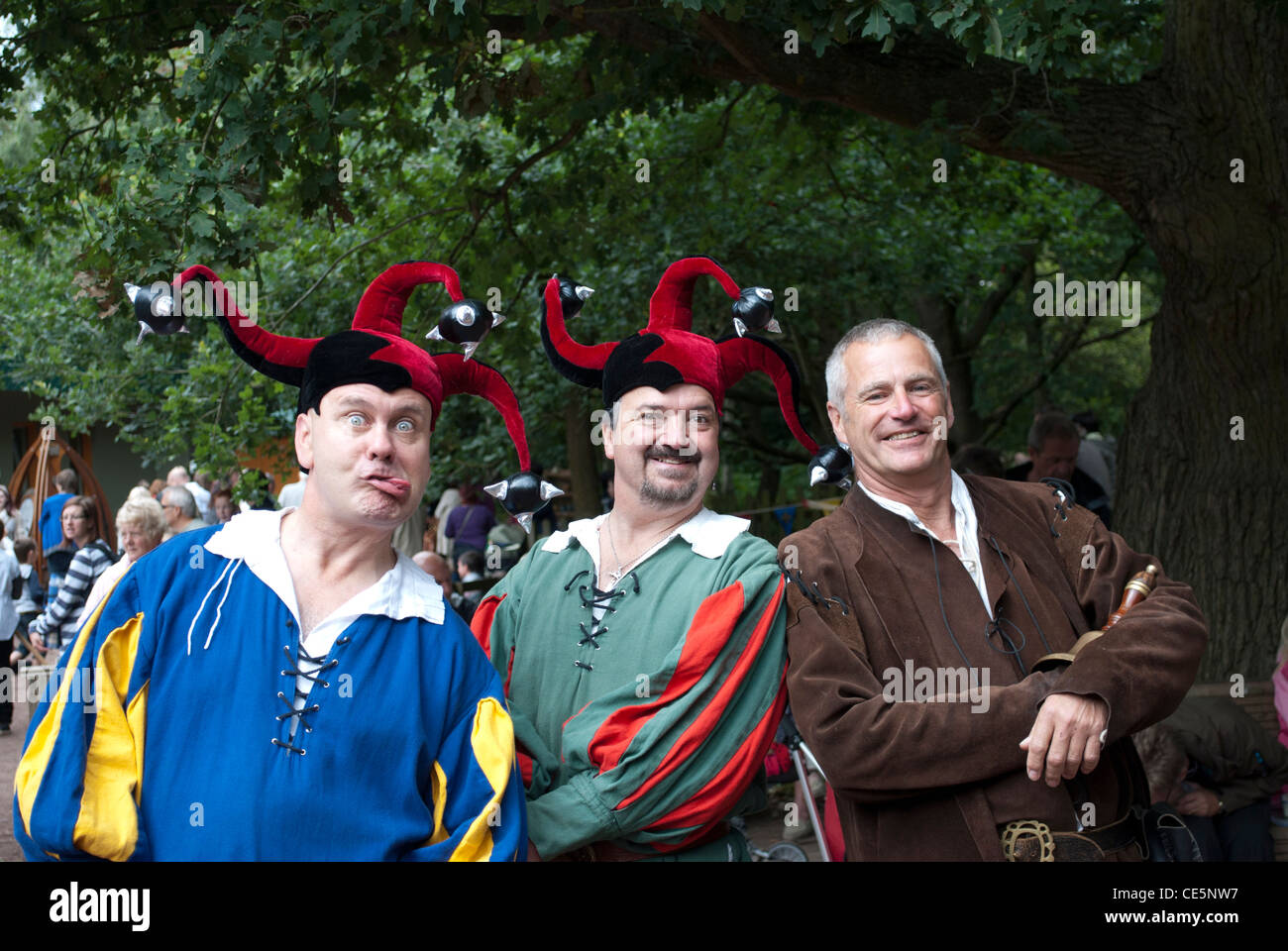 Three men, two in jester costumes, smiling, grinning and pulling faces ...
