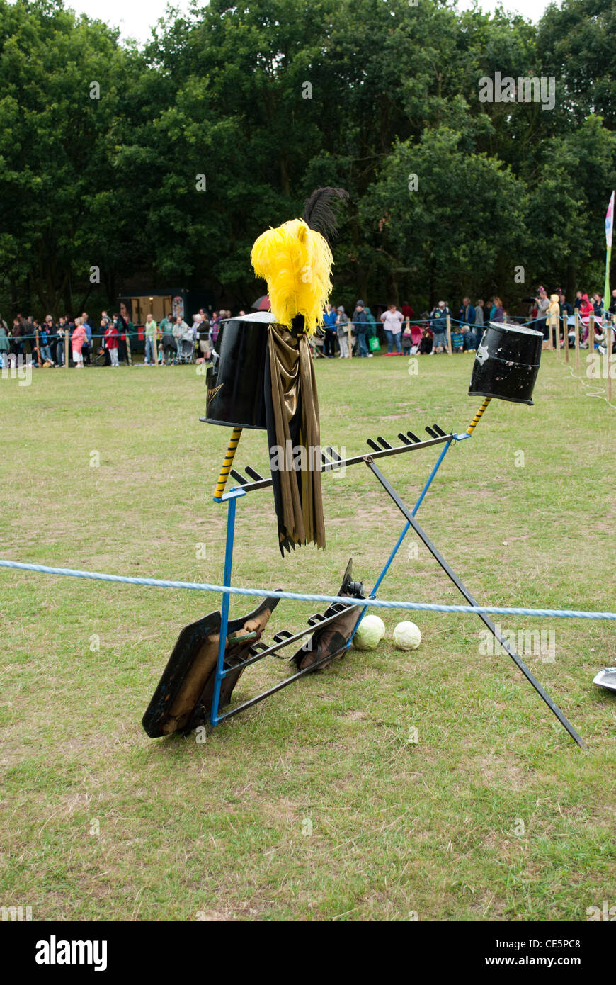 Helmets, one with yellow plume, on stand at jousting even with crowd in ...