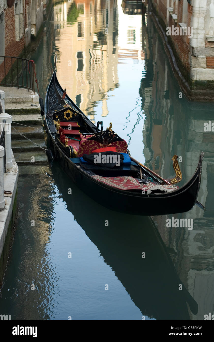 A gondola tied to a post beside steps in a narrow canal, Venice, Italy ...