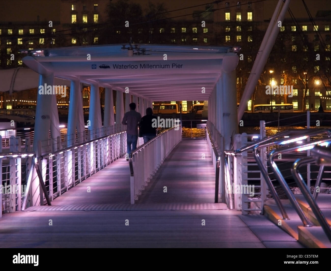 A man and walk down the illuminated Waterloo Millenium Pier on London's ...