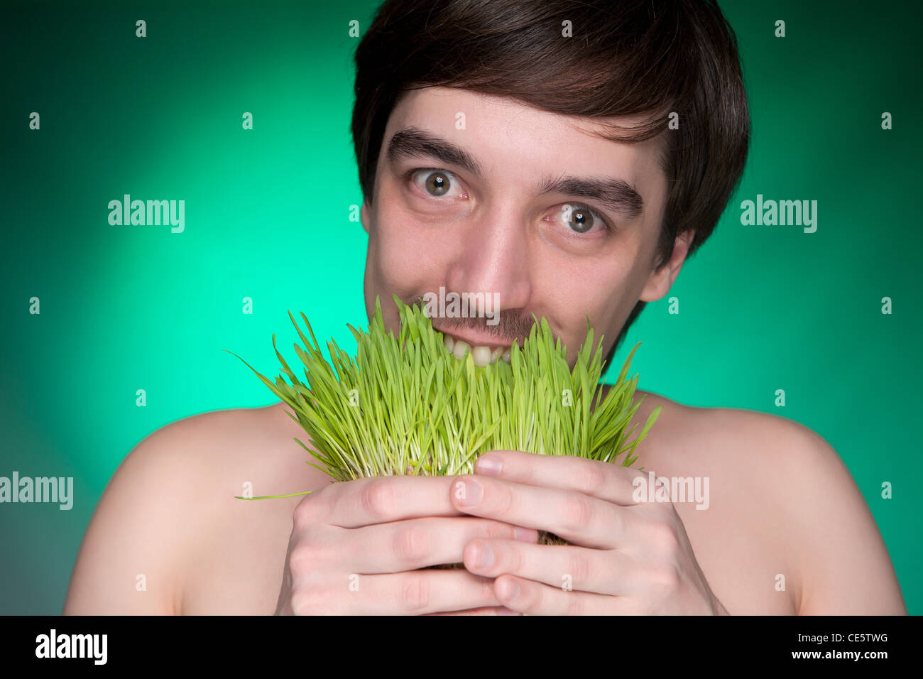 Young man eating a bunch of fresh green grass as an organic fod on a ...