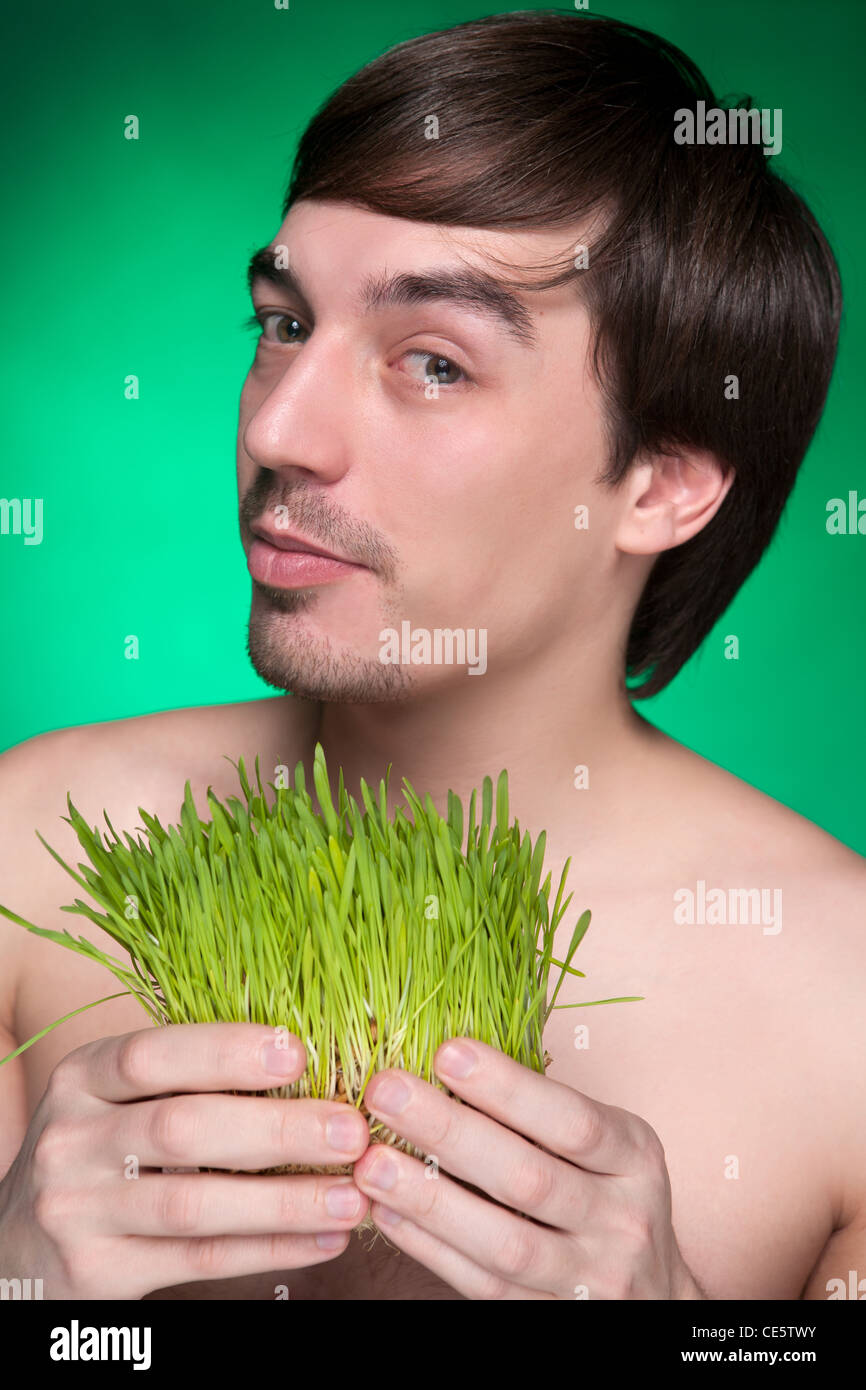 Young man with a bunch of fresh green grass as an organic food on a ...