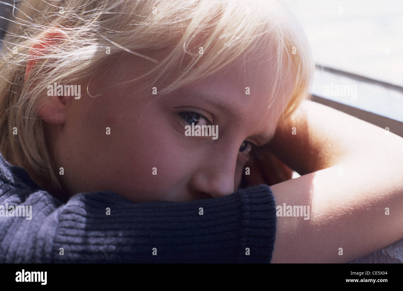 Young girl age 6 looking weary in window Stock Photo - Alamy