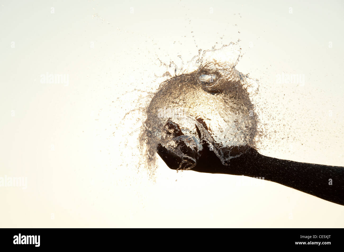 Silhouette hand holding a round burst water balloon Stock Photo - Alamy