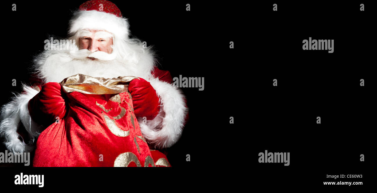 Santa sitting at the Christmas room and looking into the sack Stock ...