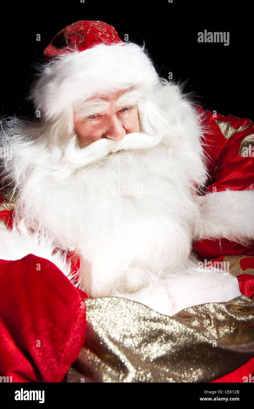 Santa sitting at the Christmas room and looking into the sack Stock ...