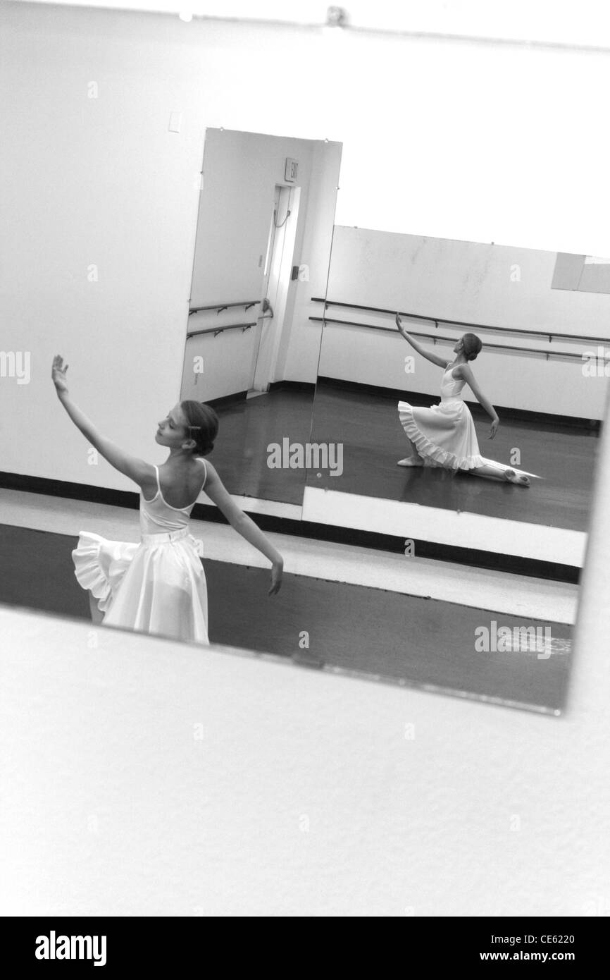 Mirror image of young female ballerina practicing in ballet studio ...