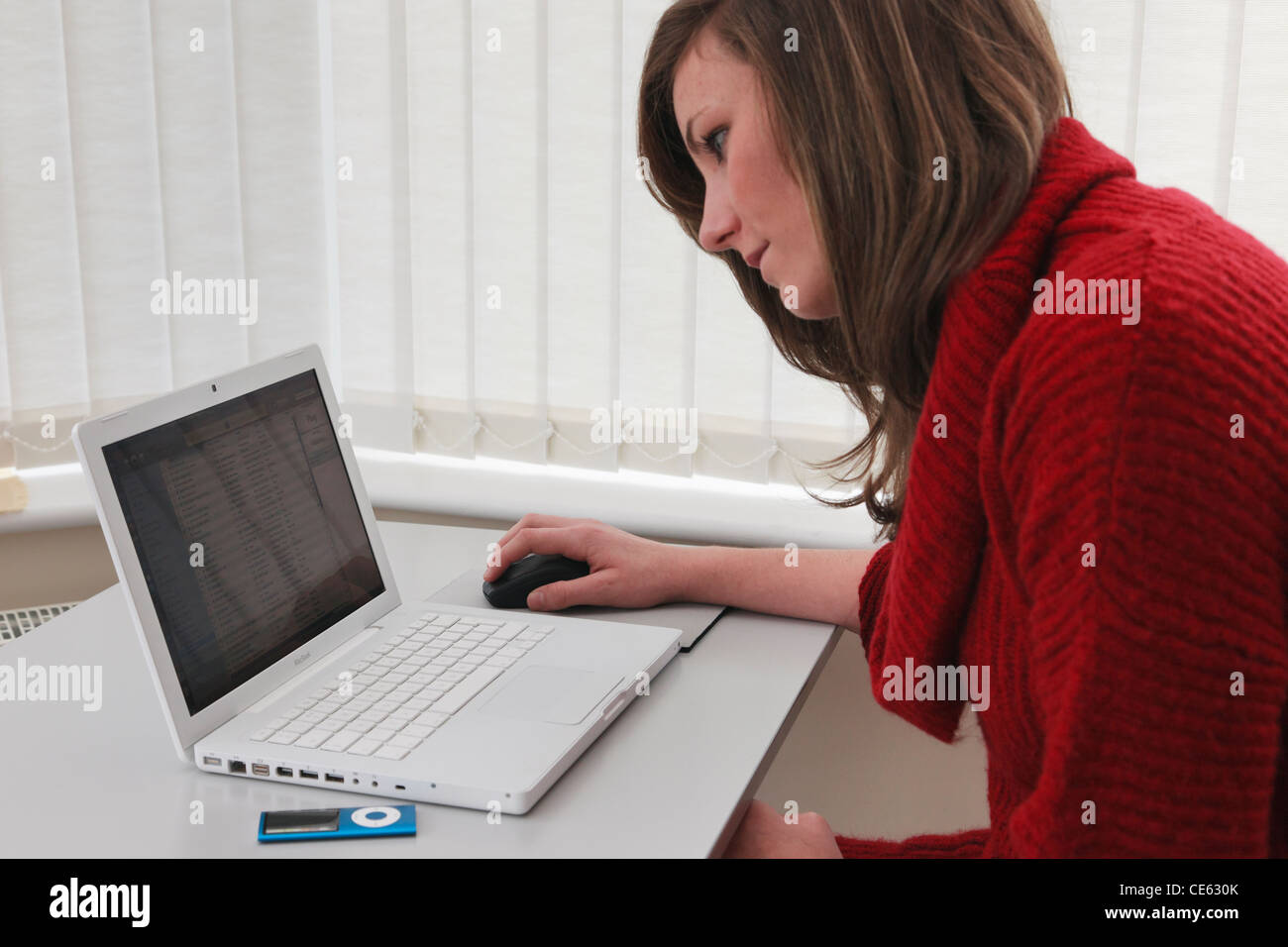 A generation z teenage girl using a white MacBook laptop computer ...