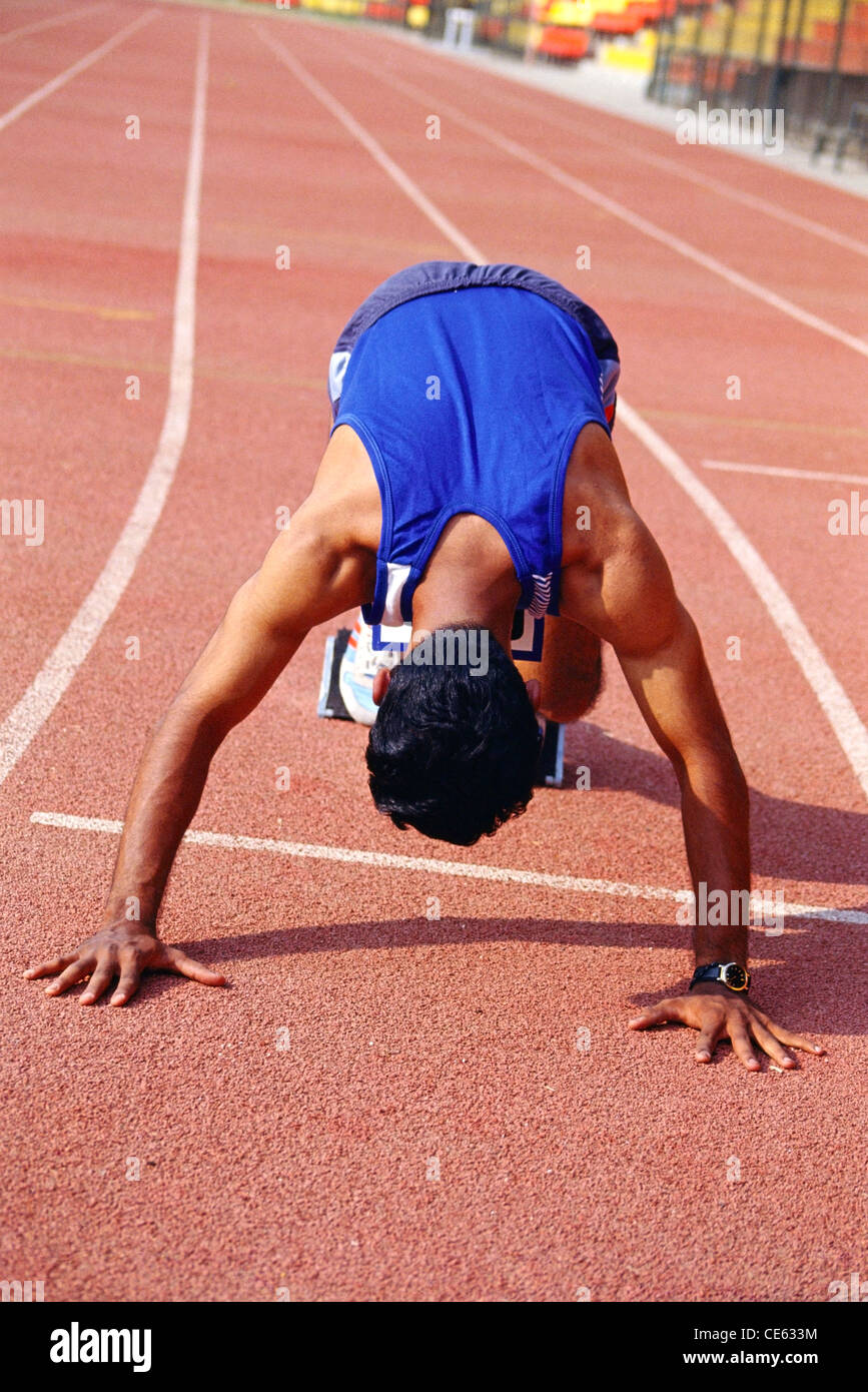 Indian teenager boy athlete runner at starting block on race track ...