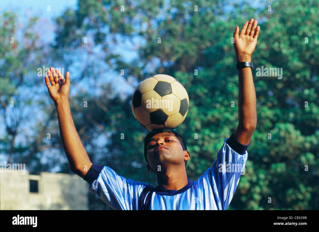 Indian teenager boy balancing football soccer ball on his head ...