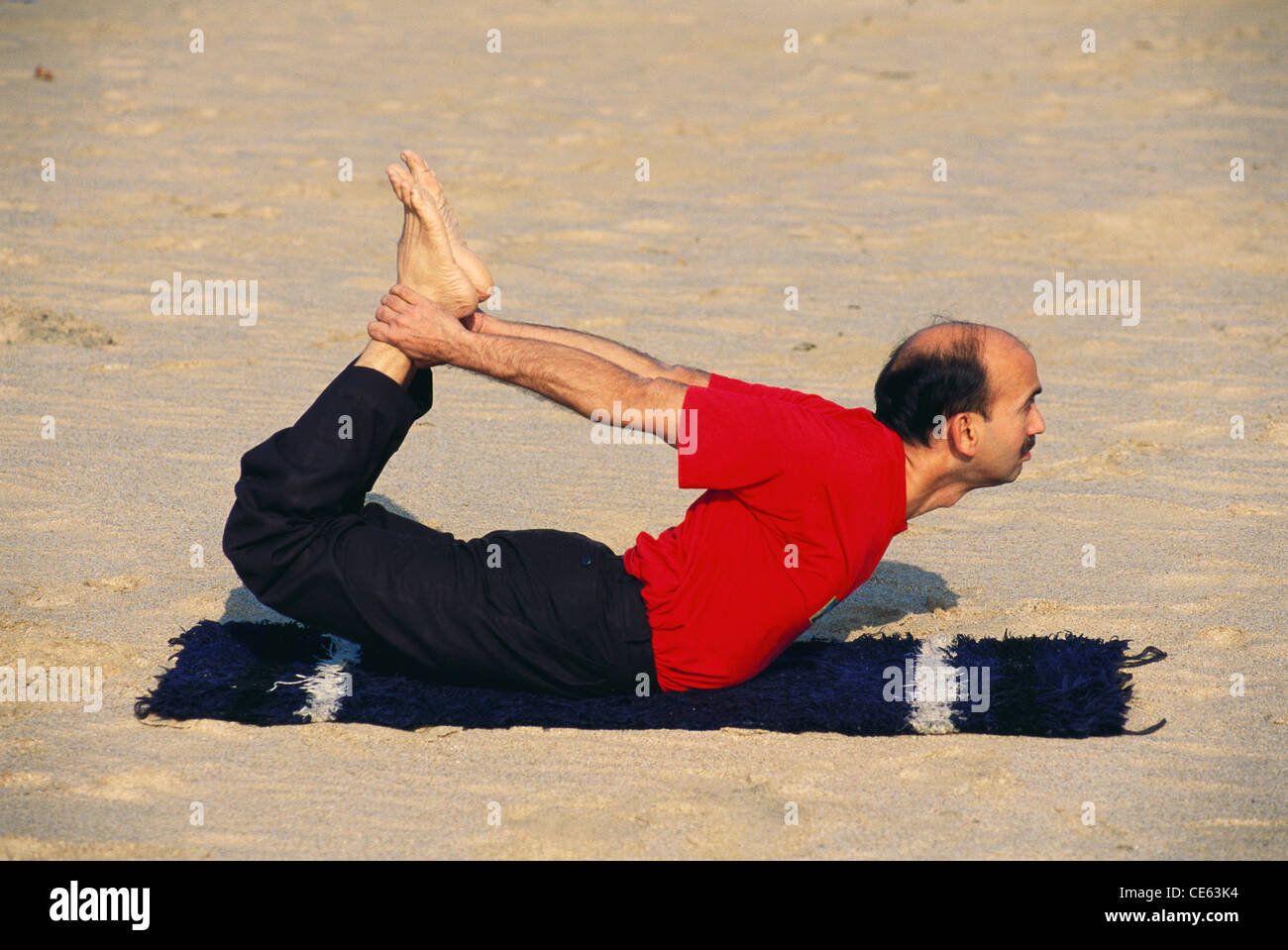 Indian man showing yoga exercise posture dhanur asana ; Dhanurasana ...