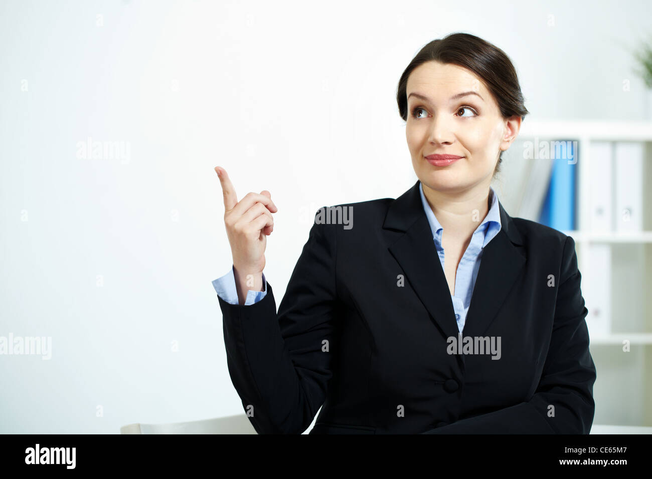 Portrait of happy office worker looking aside while pointing upwards ...
