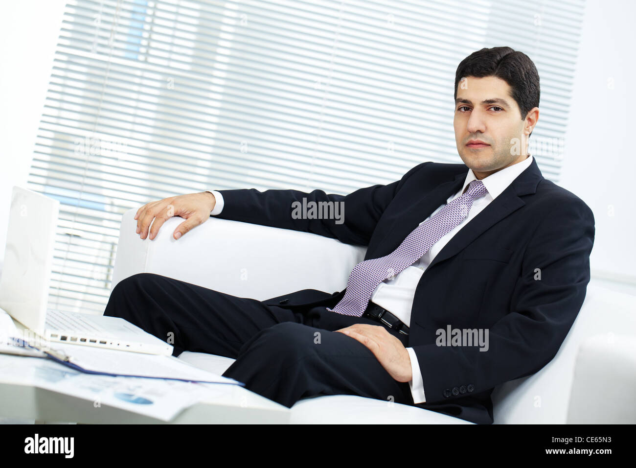 Portrait of attractive businessman in suit sitting in office Stock ...