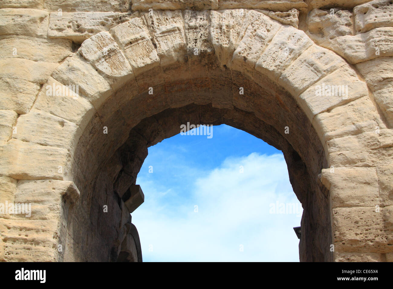 An ancient Roman arch of travertine on a background of a blue sky with ...