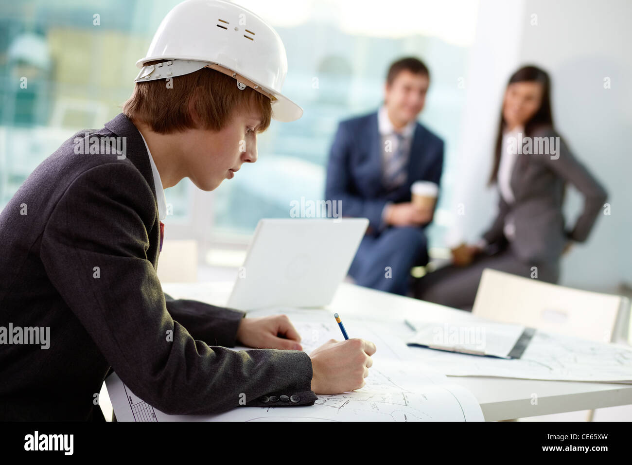 Young engineer working in office with his colleagues on background ...