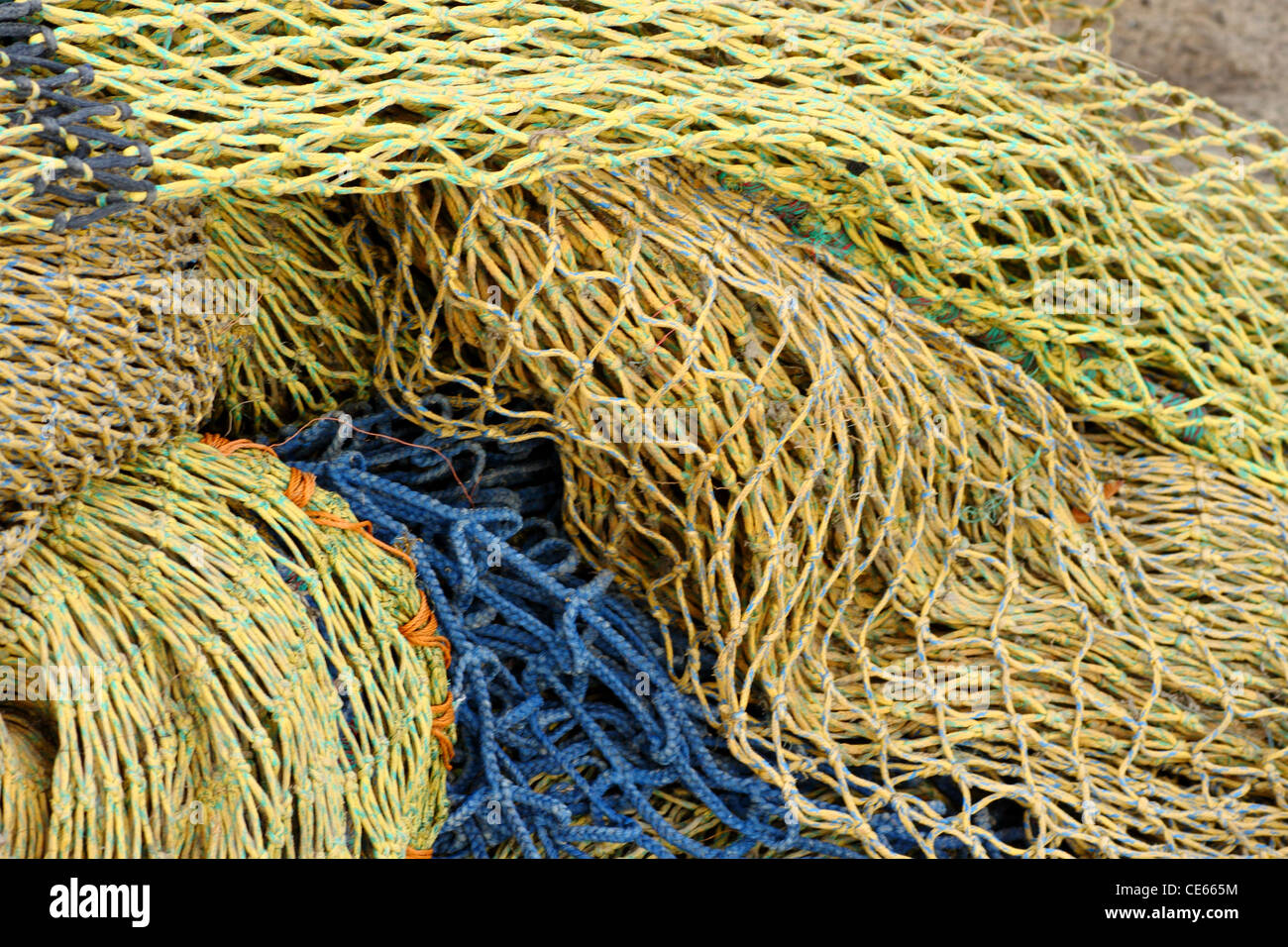 A pile of old yellow fishing nets with a single blue net Stock Photo ...