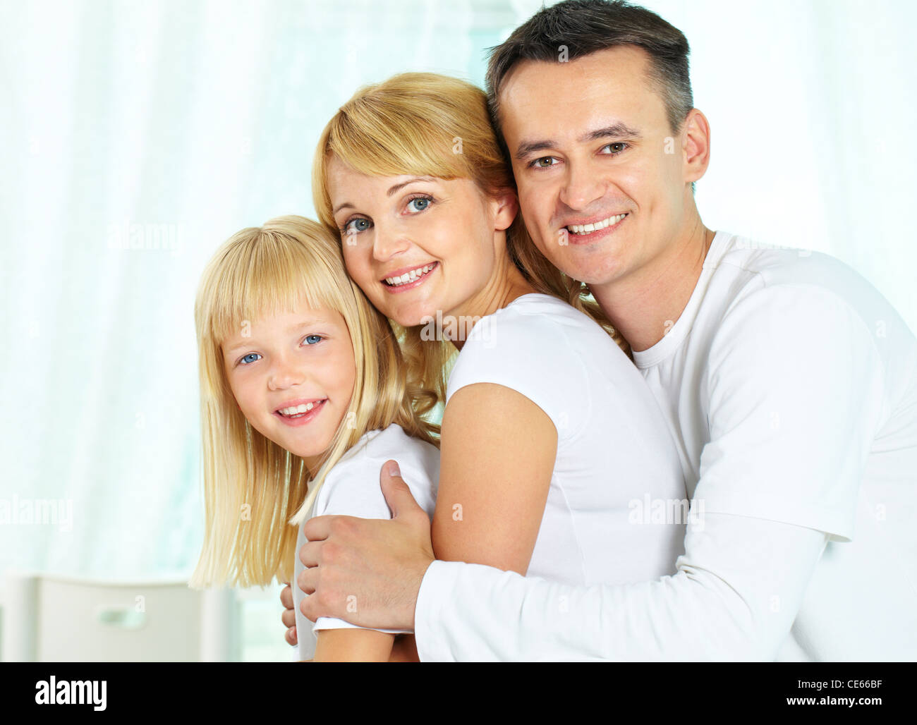 Portrait of happy parents and their daughter looking at camera with ...