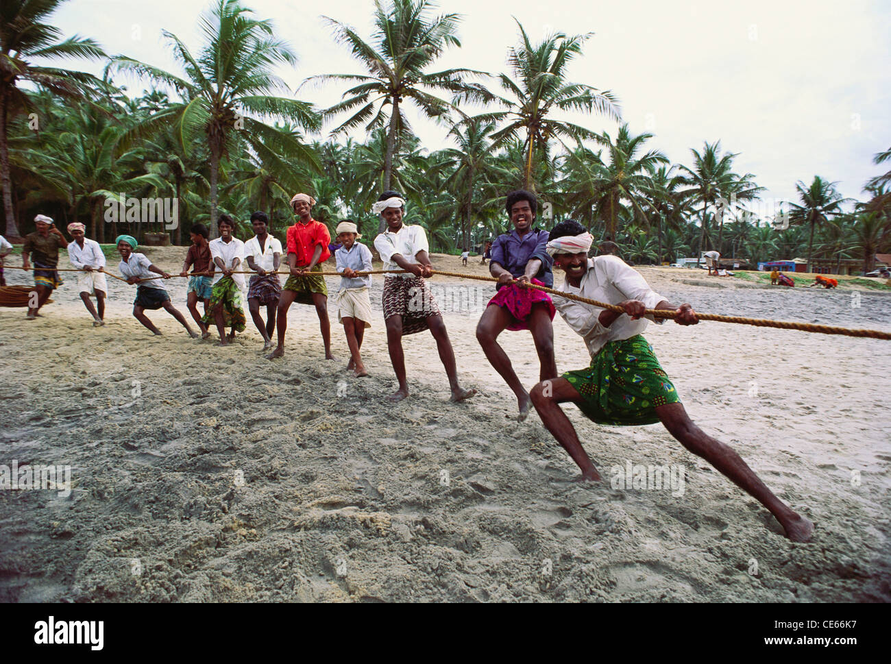Fishermen pulling rope to pull fishing net with their catch of fish ...
