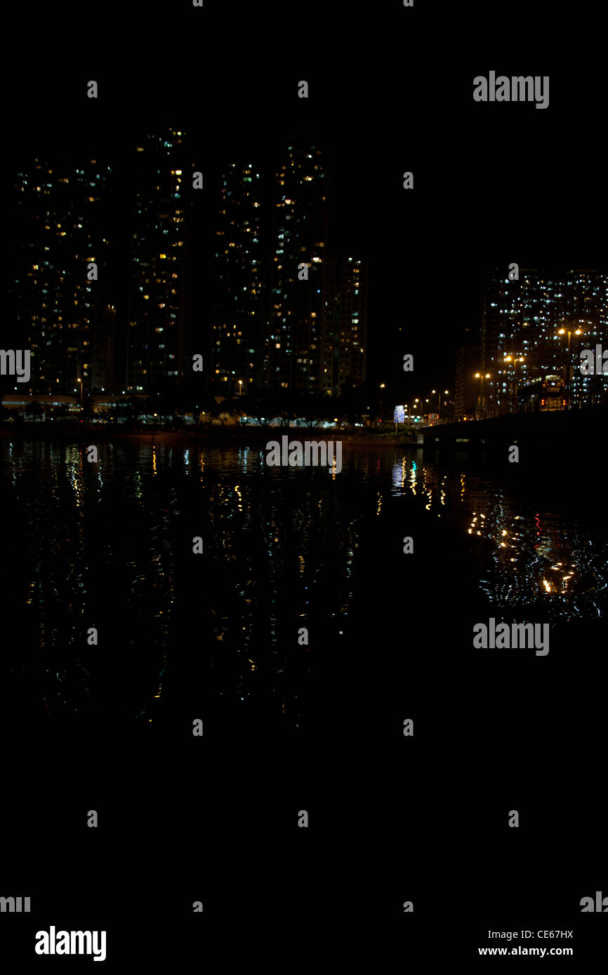 Lights of tower blocks and city lights at night reflected in the Shing ...