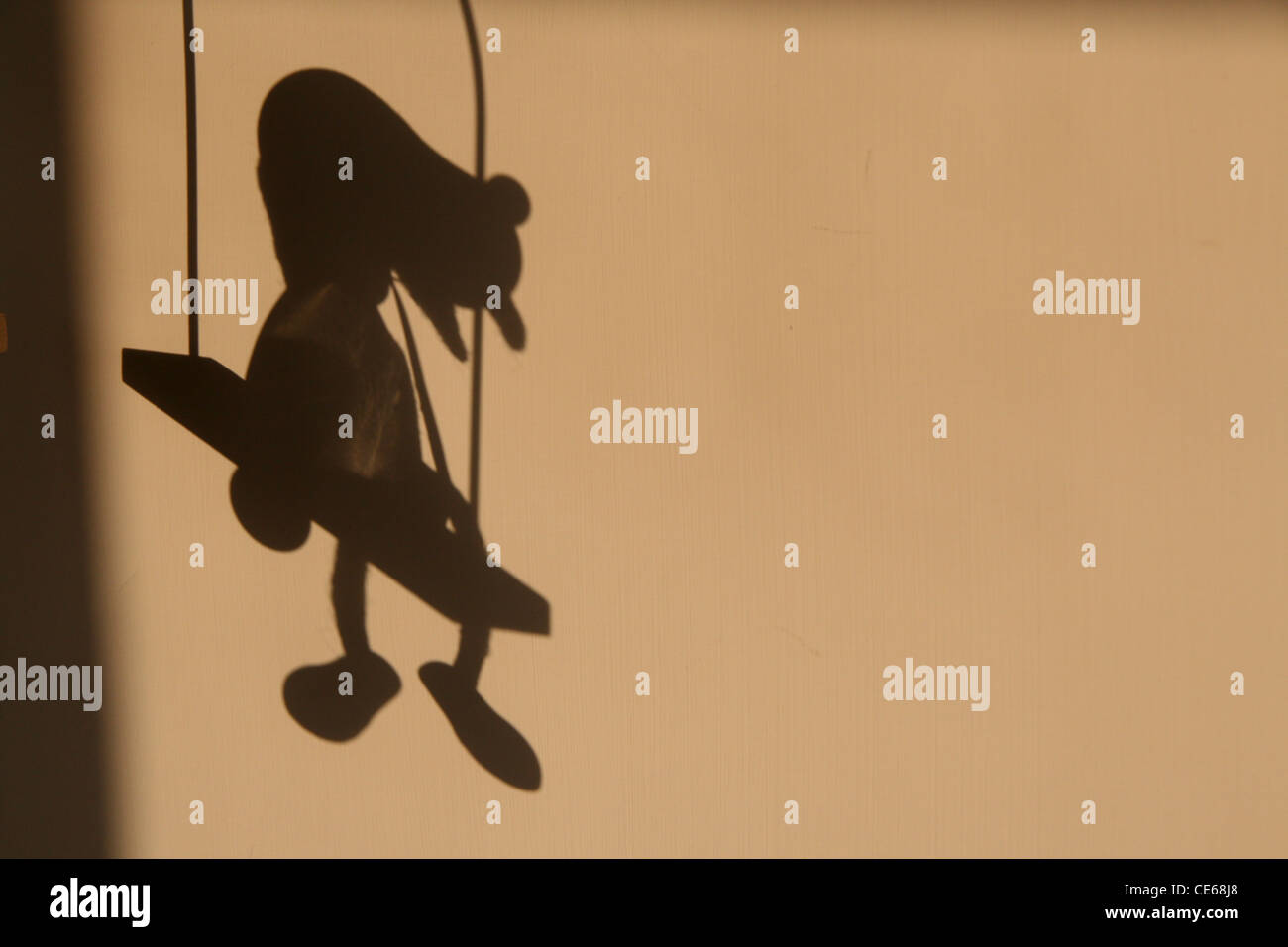 shadow of toy dog sitting on a swing on wall Stock Photo - Alamy