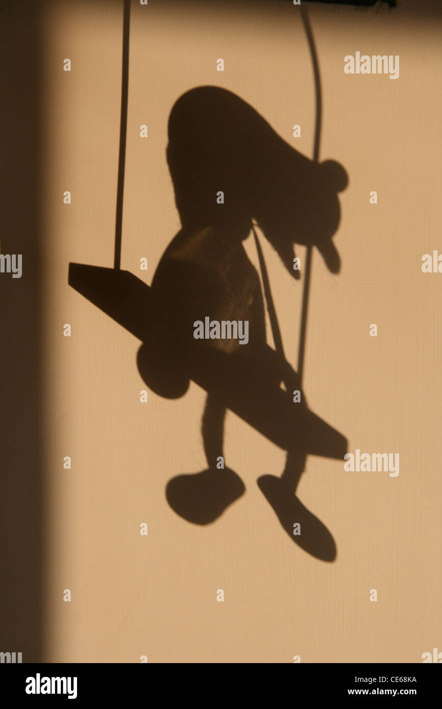 shadow of toy dog sitting on a swing on wall Stock Photo - Alamy