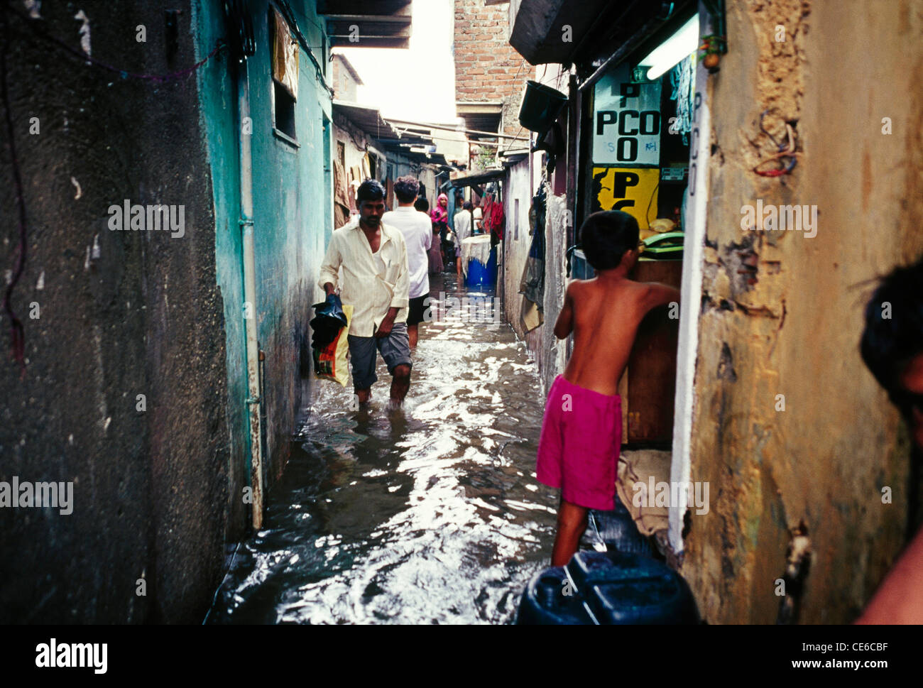 small lane in slums flooded in monsoon rain ; bombay mumbai ...