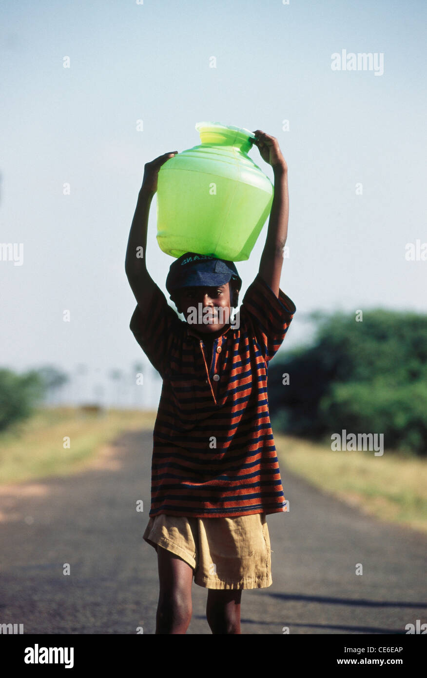 Boy balancing green plastic water pot on his head India Stock Photo - Alamy