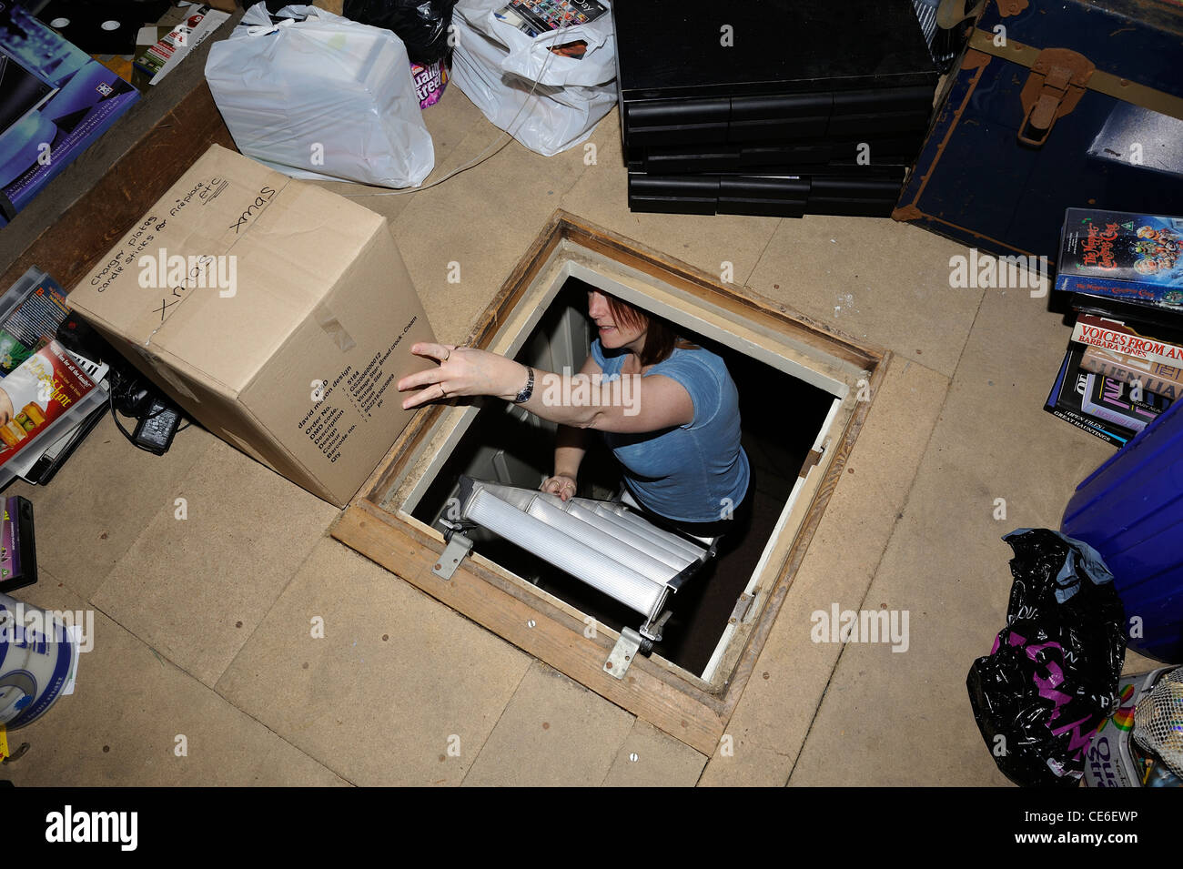 female placing a box into the attic loft area of a house england uk ...