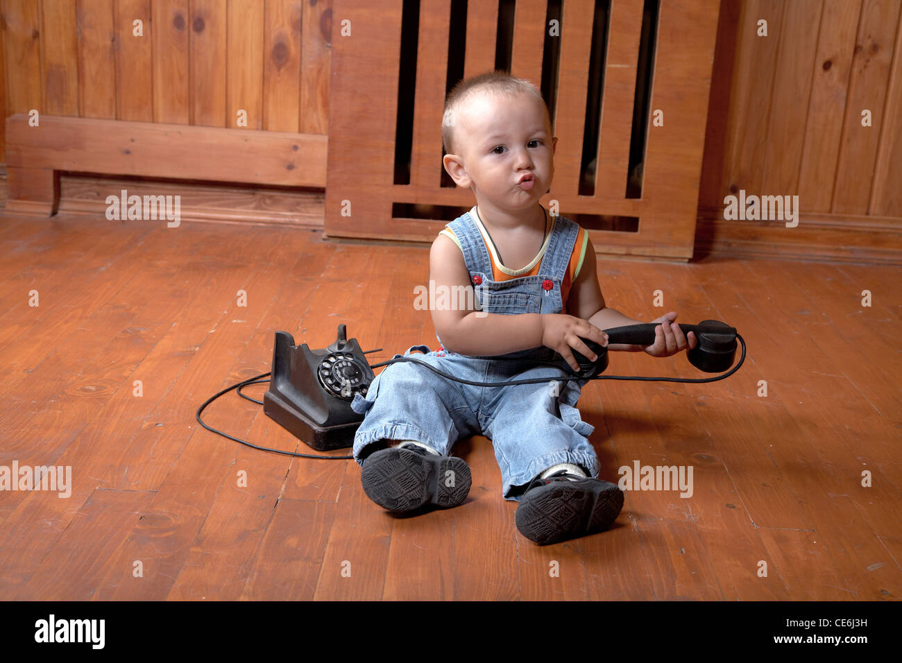 The little boy plays old phone sitting on a floor Stock Photo - Alamy