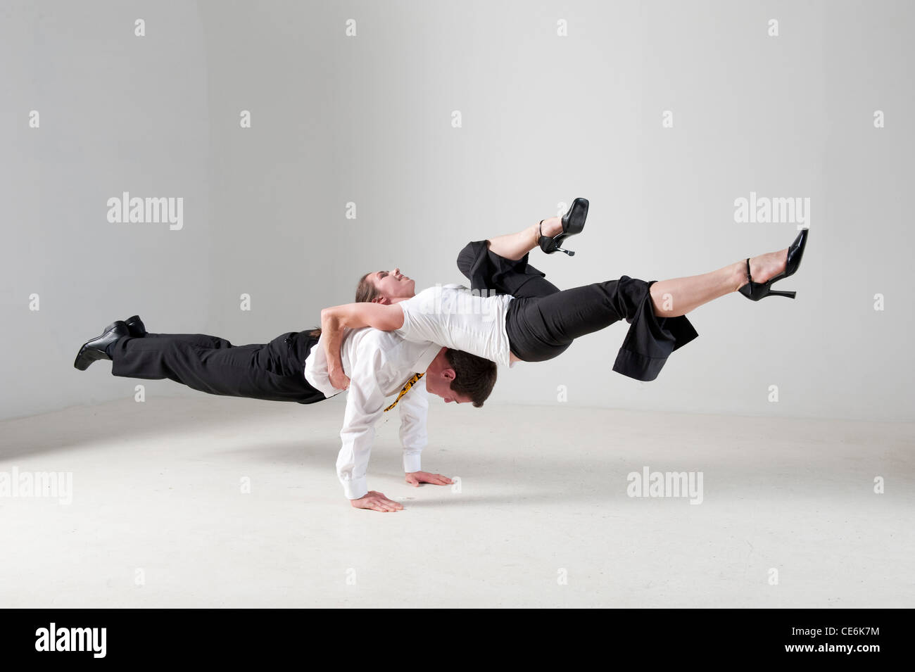 photograph of acrobatic businessman and women performing balancing act ...