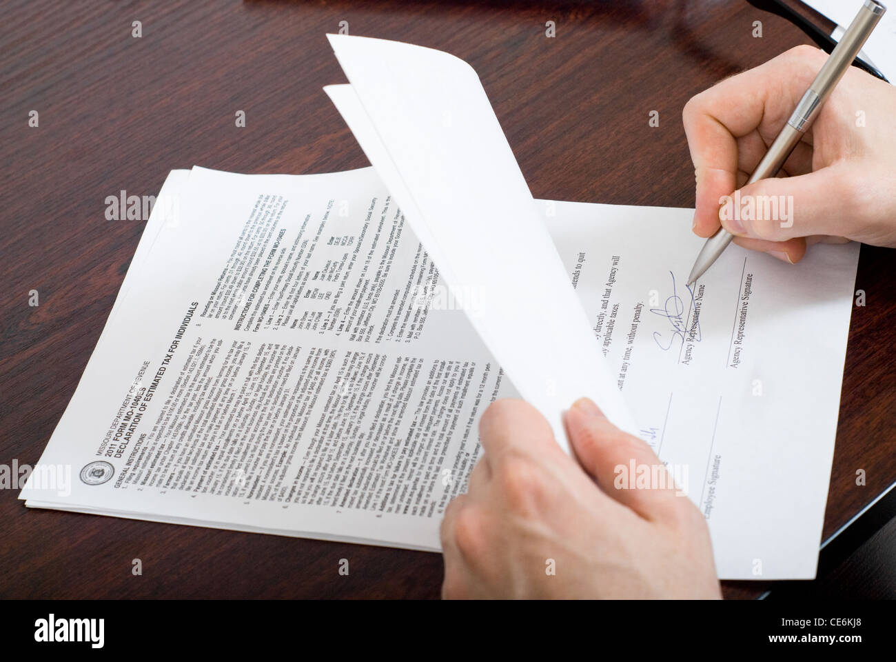 Business man signing all pages of 1040 tax form Stock Photo - Alamy