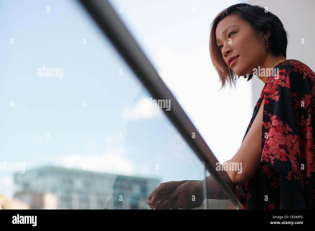Young woman looking over balcony Stock Photo - Alamy
