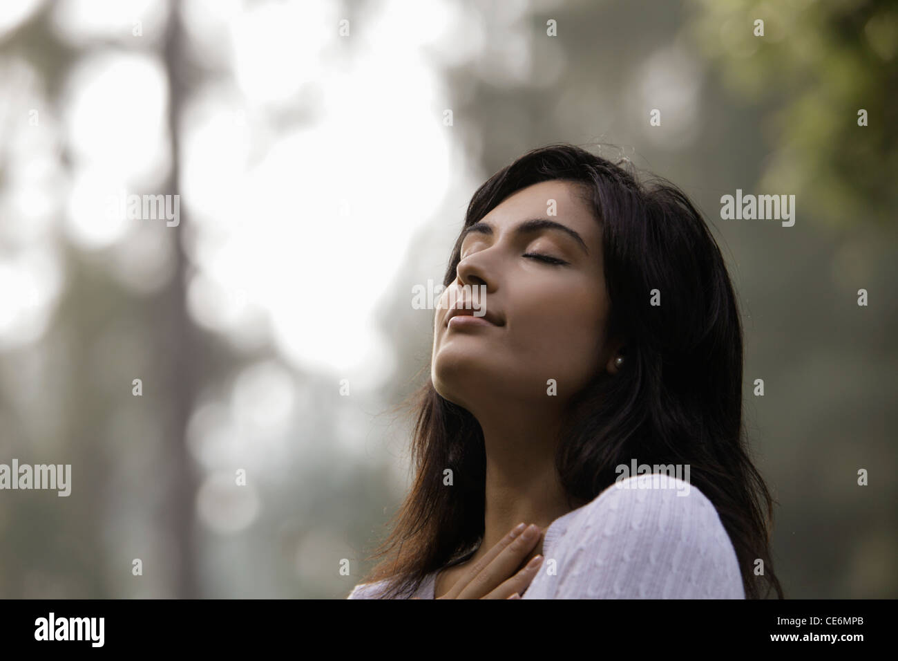 Back lit head shot of young woman with eyes closed outdoors Stock Photo ...