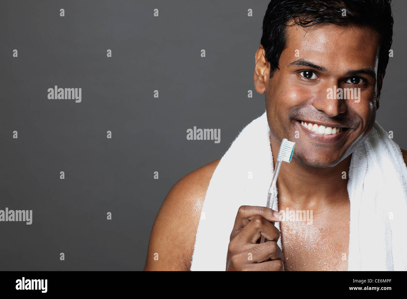 Head shot of man smiling holding toothbrush Stock Photo - Alamy