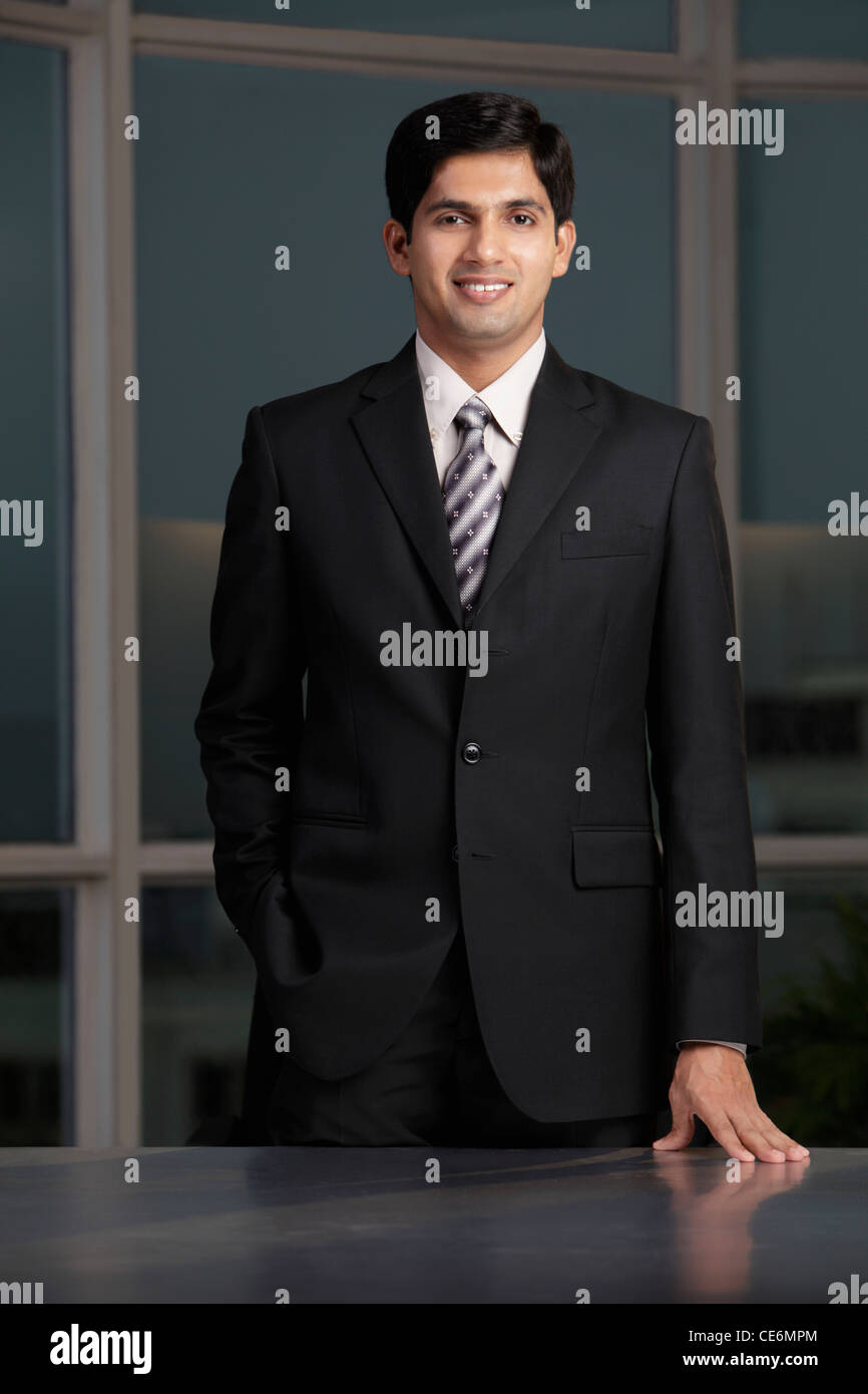 young man smiling and standing at desk Stock Photo - Alamy