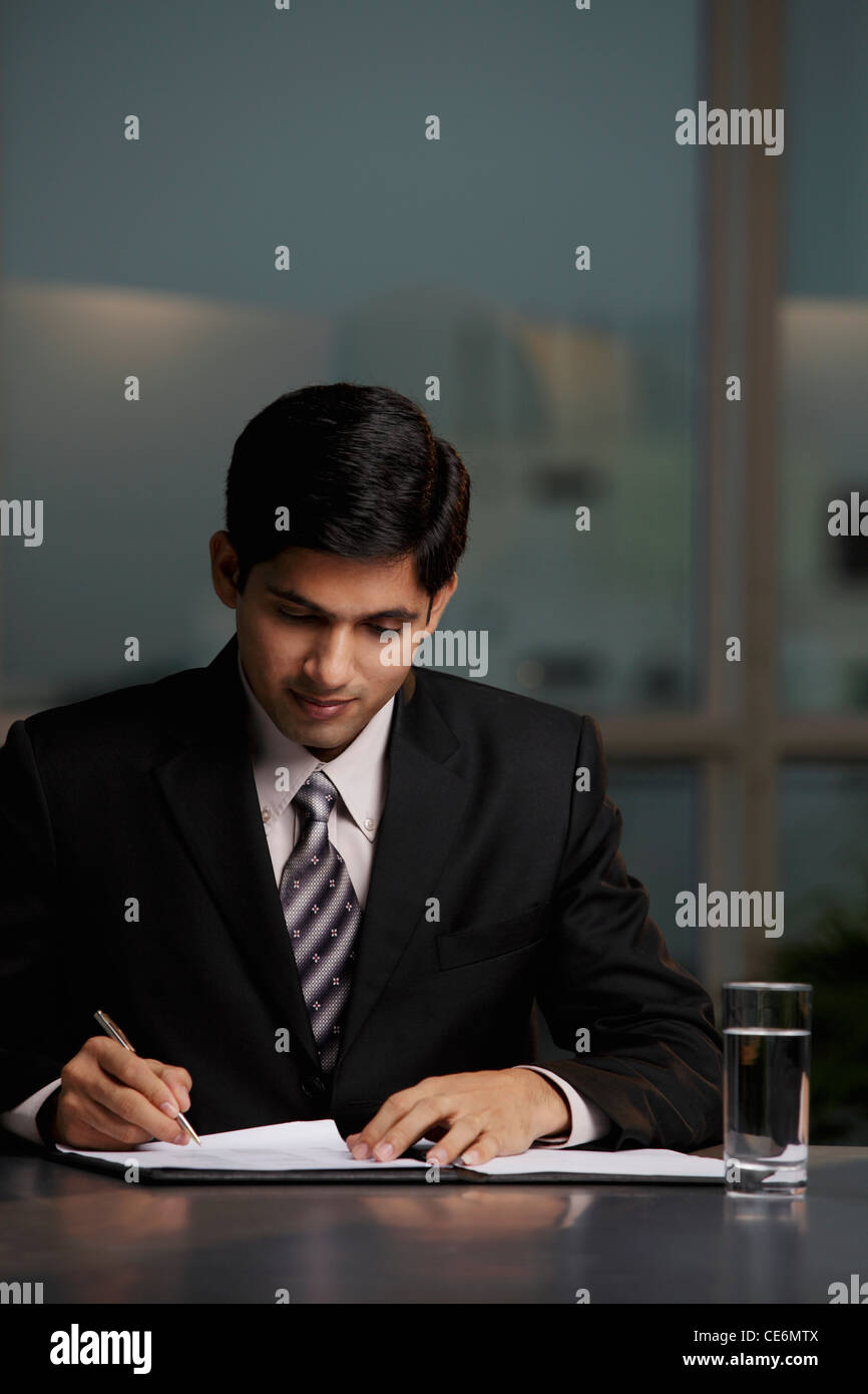 Indian man writing at table Stock Photo - Alamy