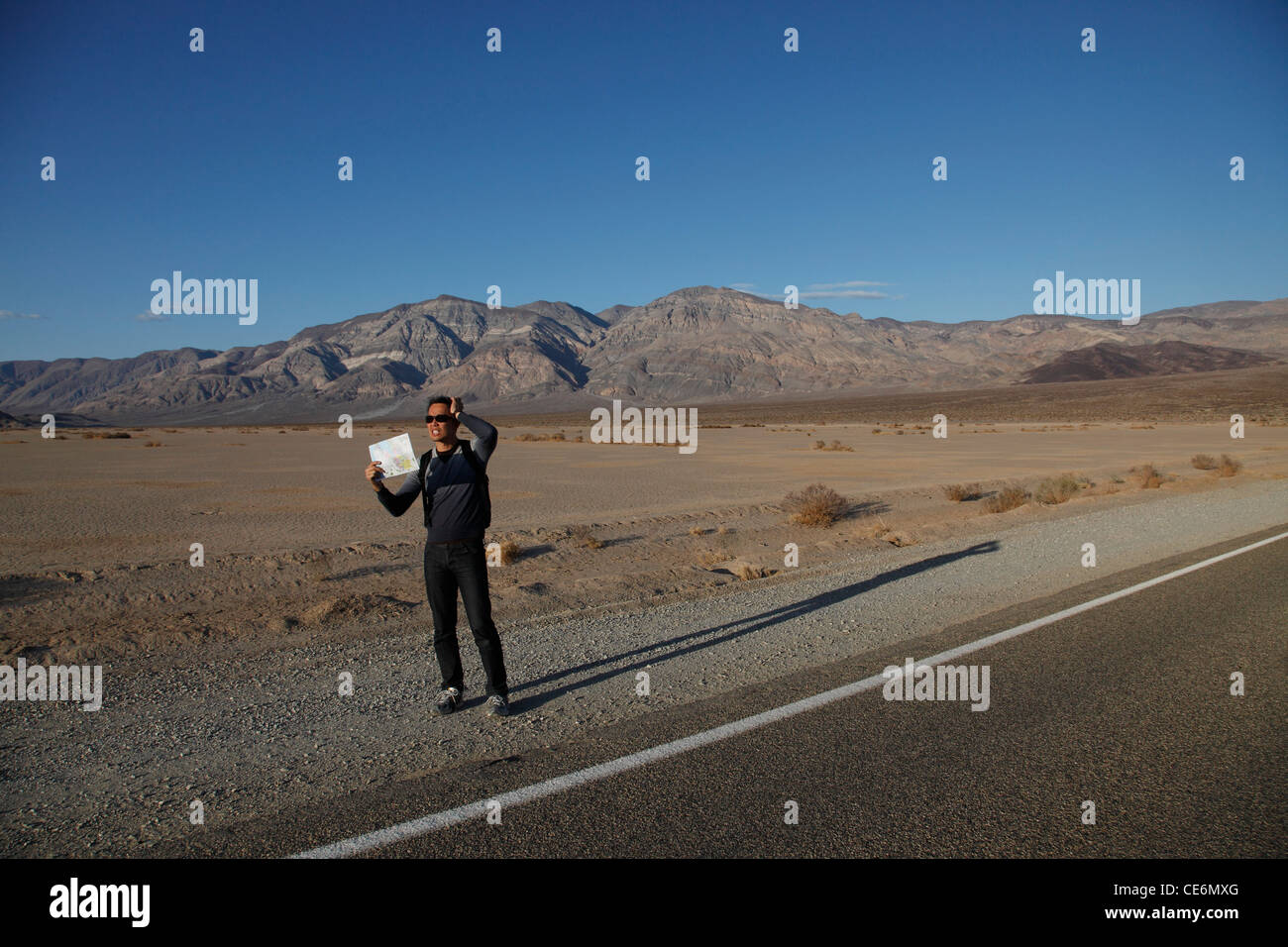 Man holding map on the side of the road in the desert Stock Photo - Alamy