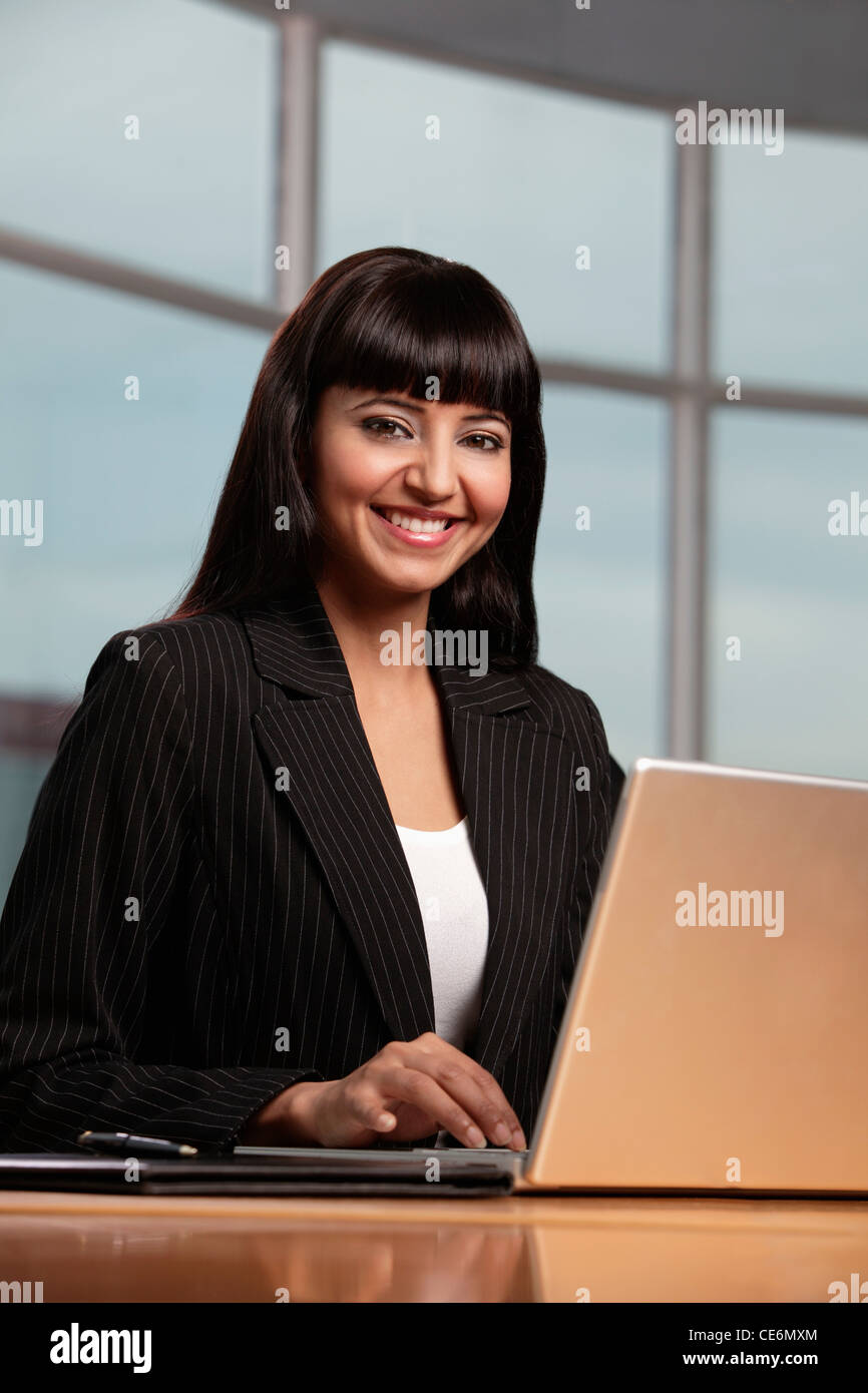 Indian woman smiling and working on laptop Stock Photo - Alamy