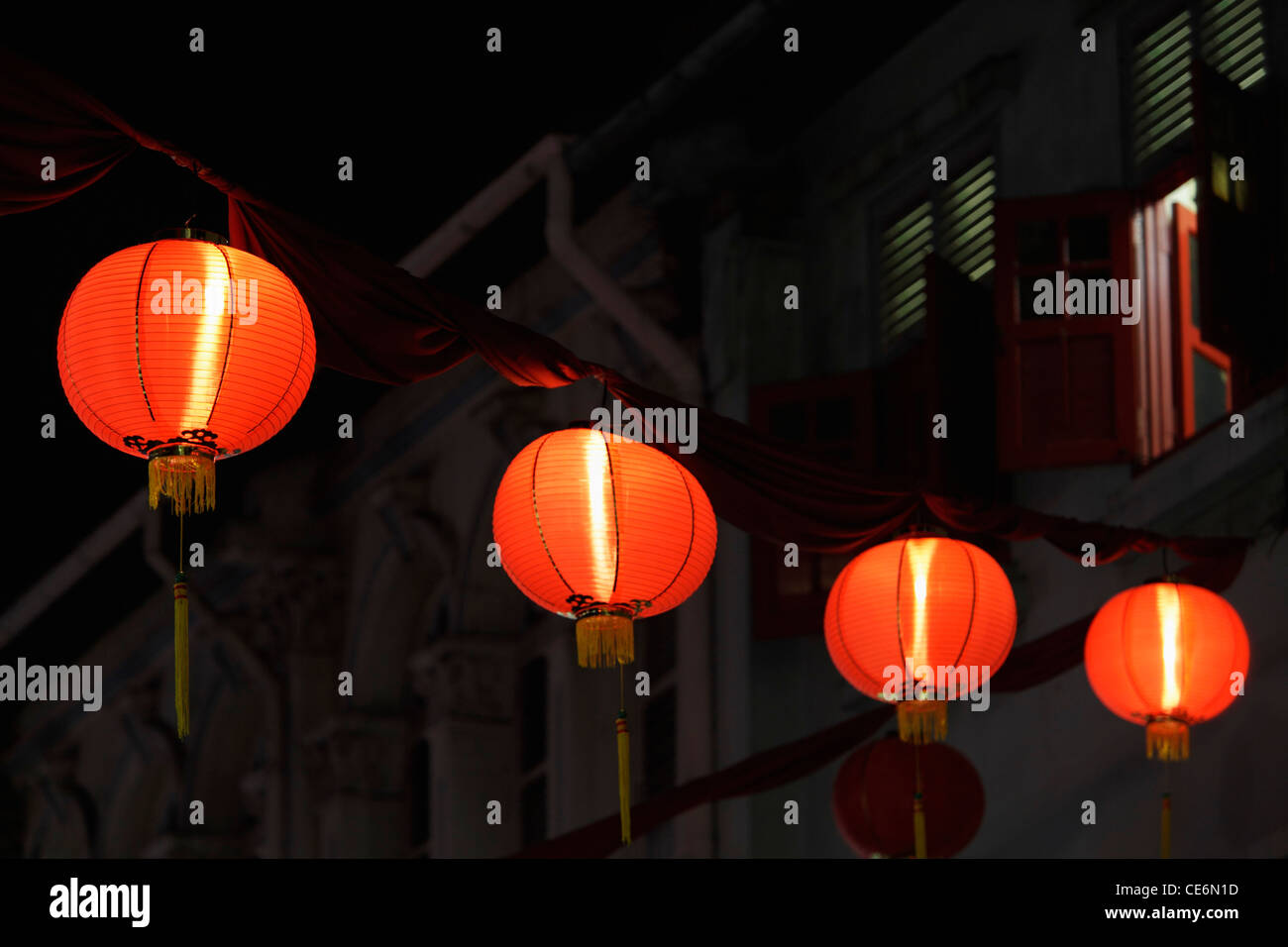Red lanterns glowing at night above the street Stock Photo - Alamy