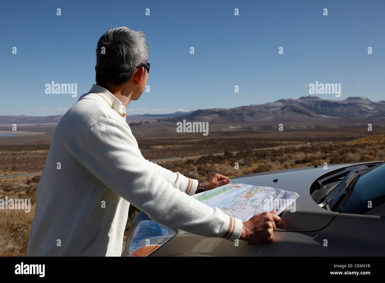 Back view of man looking at a map by his car Stock Photo - Alamy