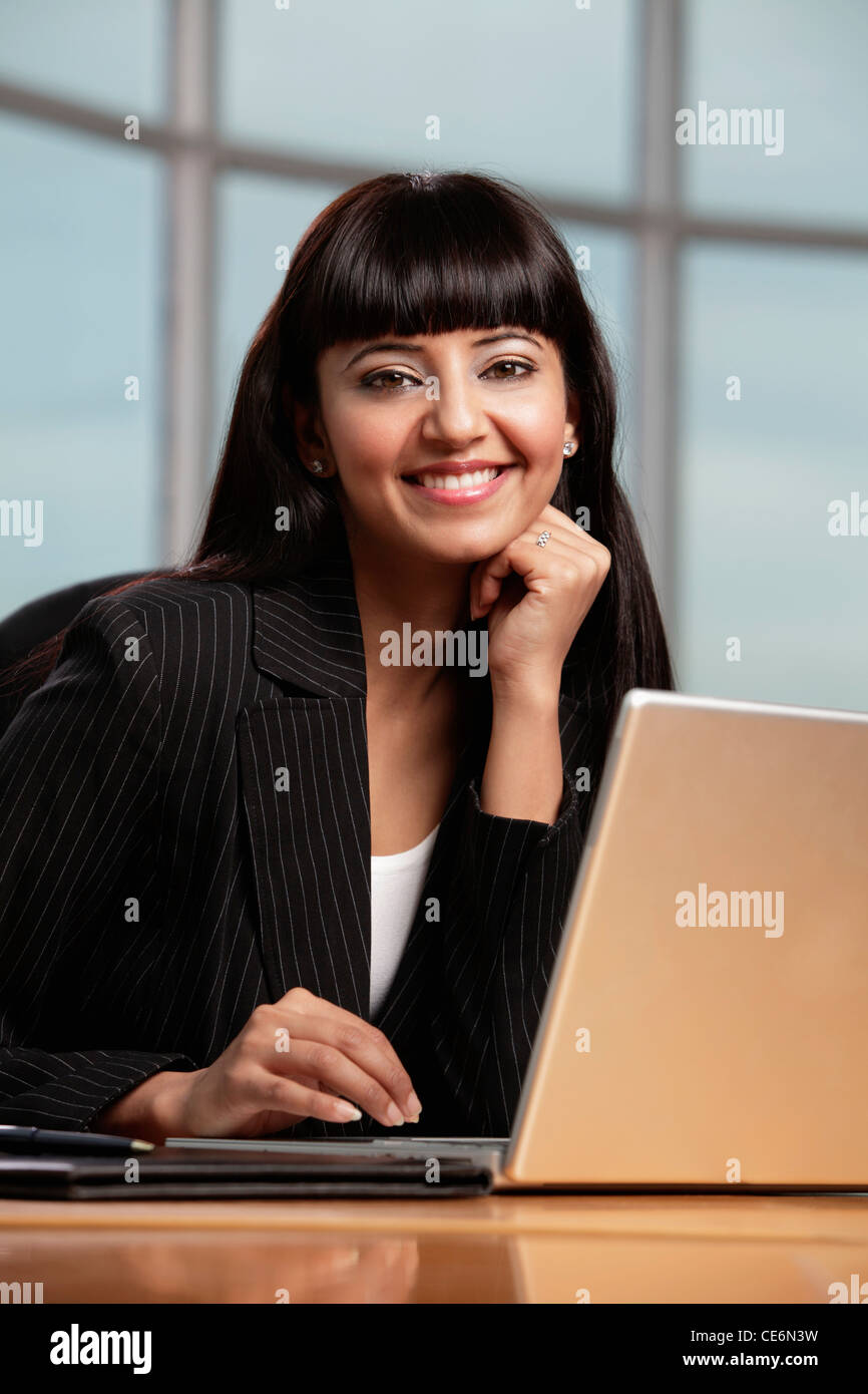 Indian woman smiling while working on laptop Stock Photo - Alamy