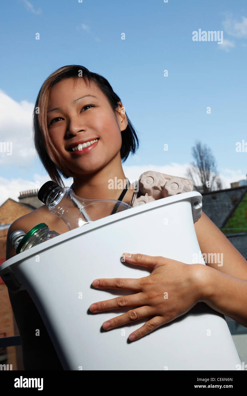 Young woman holding rubbish bin for recycling Stock Photo - Alamy
