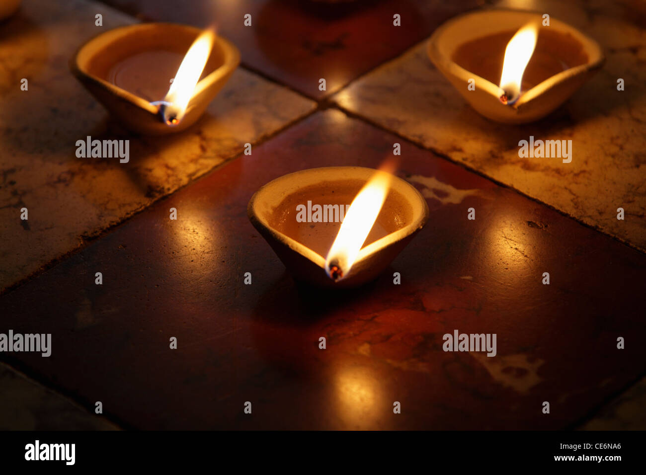 Lit clay oil lamps on floor Stock Photo - Alamy