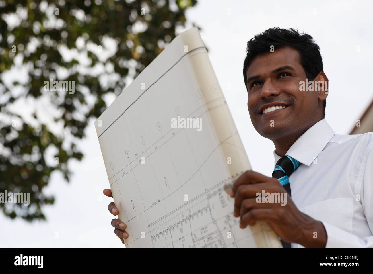 Business man holding plans and smiling outside Stock Photo - Alamy