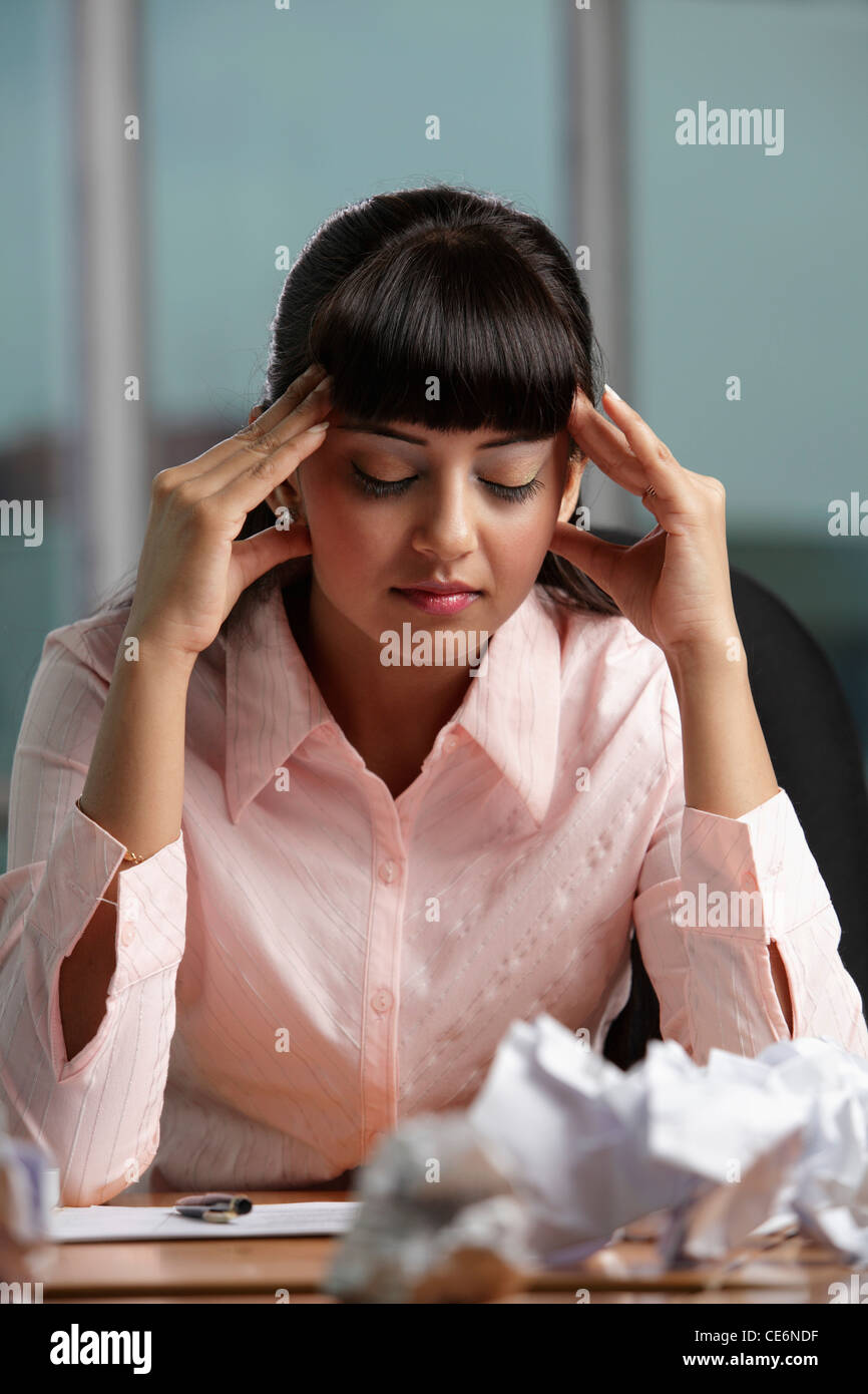Indian woman holding her head at work Stock Photo - Alamy