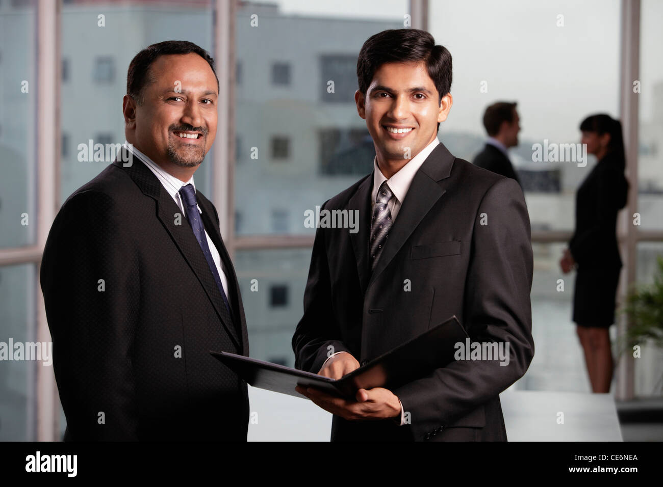 Indian men discussing business, colleagues in background Stock Photo ...